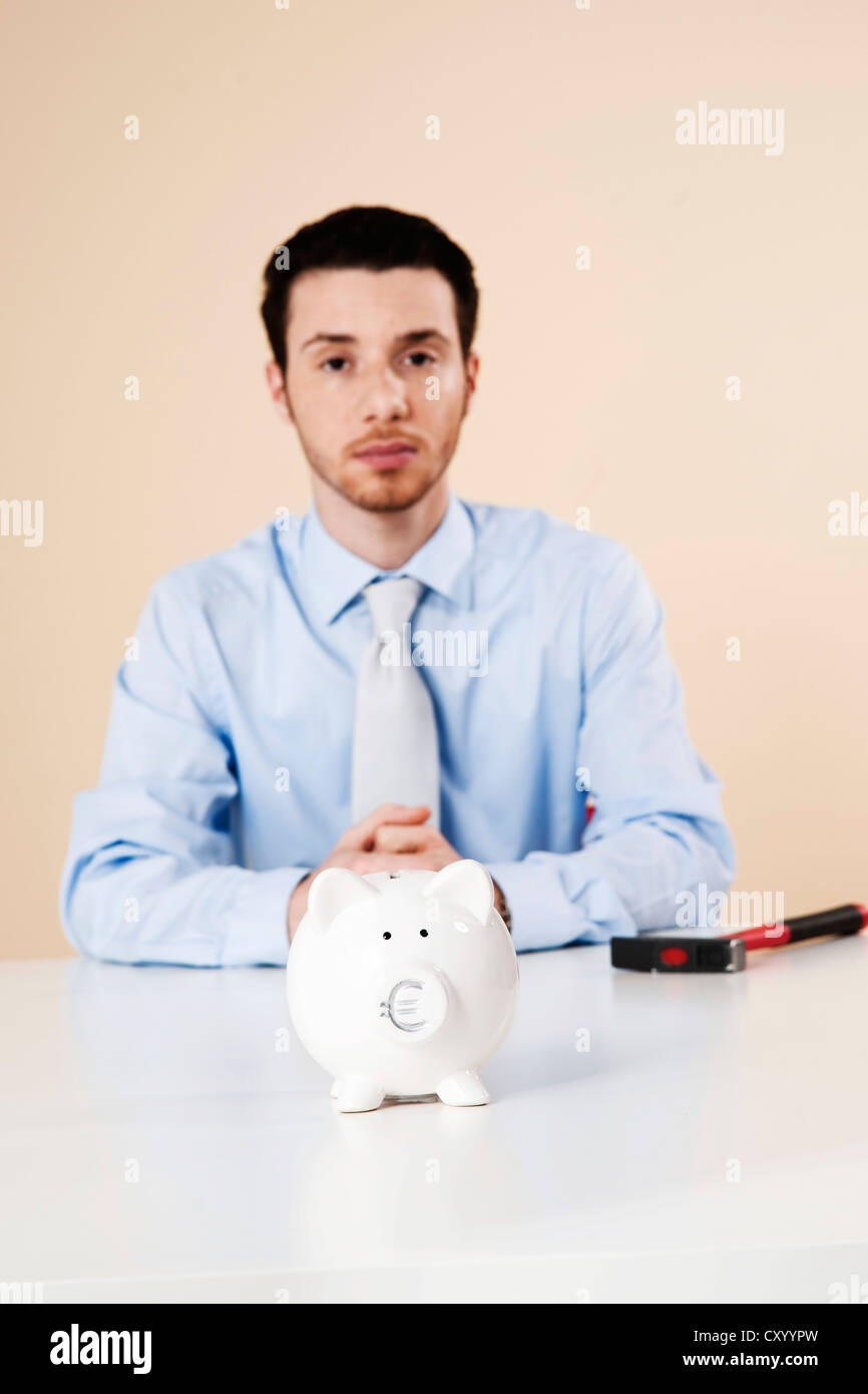 Young man with a concerned expression sitting behind a piggy bank Stock ...