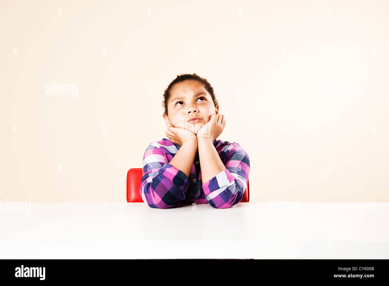 Girl sitting and thinking at a table Stock Photo - Alamy