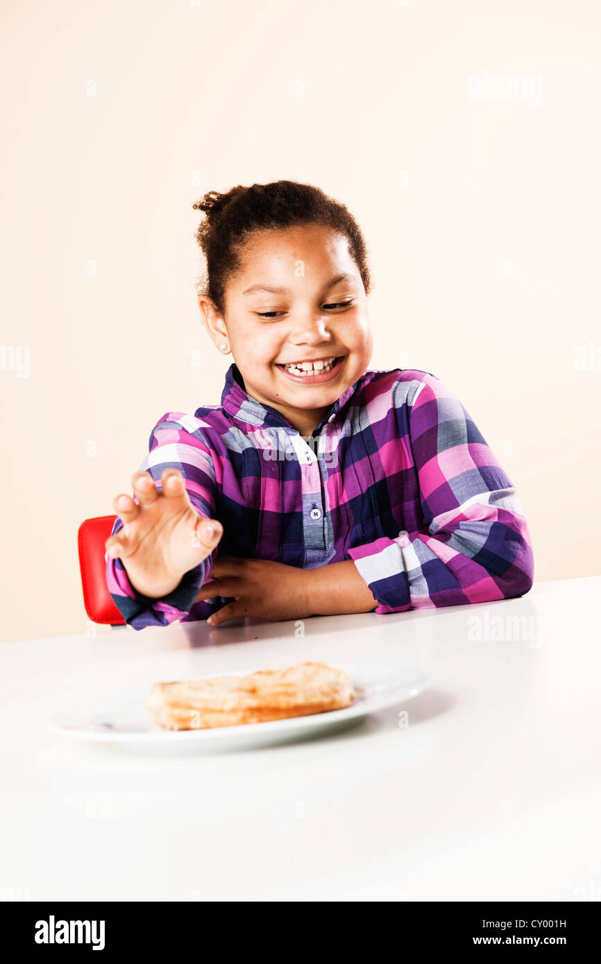 Girl deciding to eat a piece of sweet pastry Stock Photo - Alamy