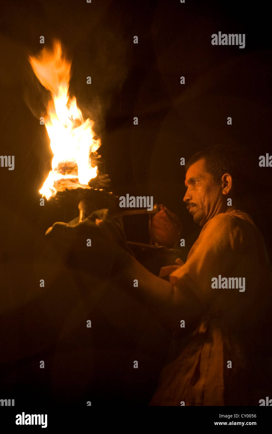 A Hindu Pujari (priest) raises flaming offerings from worshippers at ...
