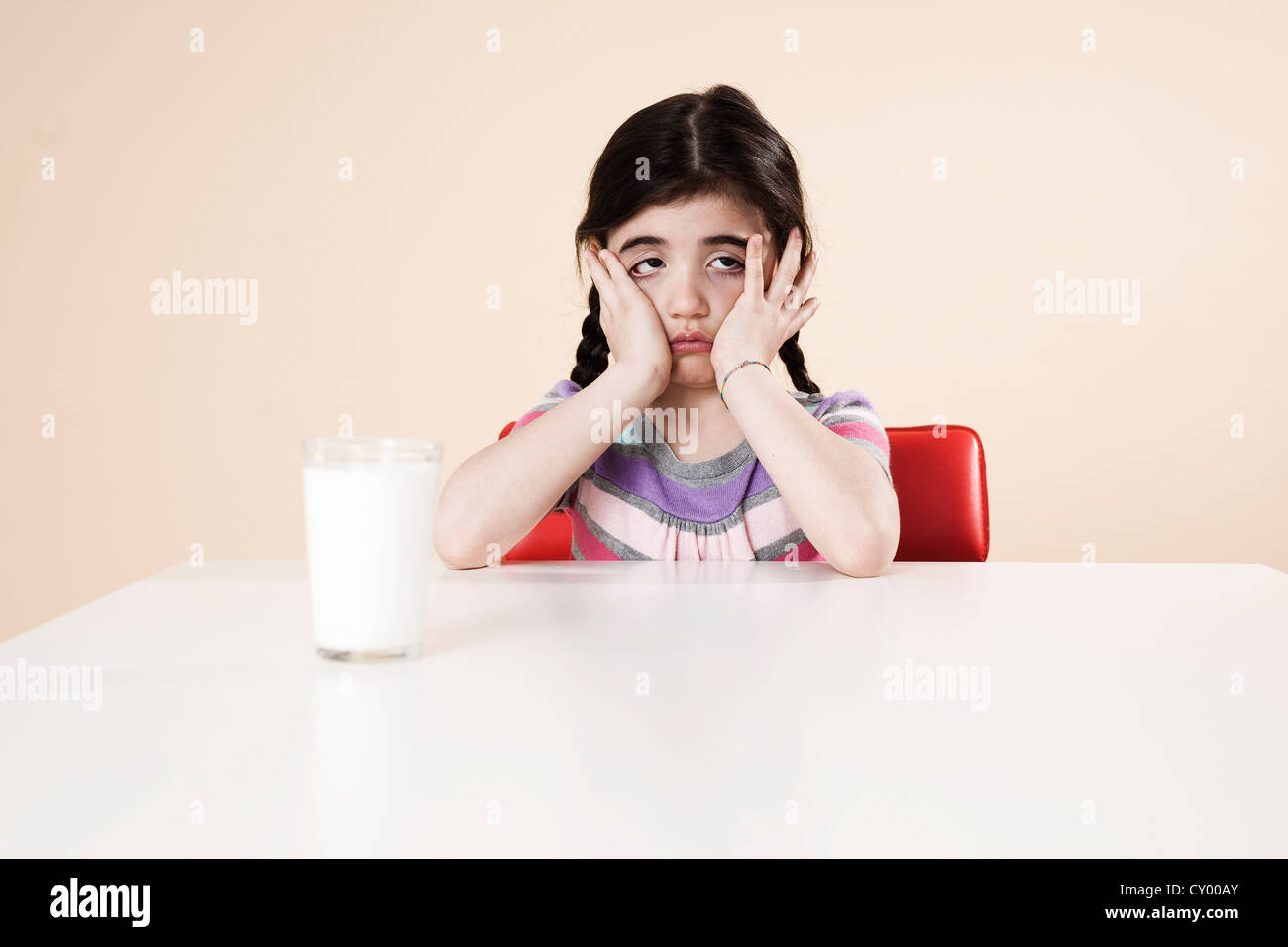 Girl looking listlessly at a glass of milk Stock Photo - Alamy