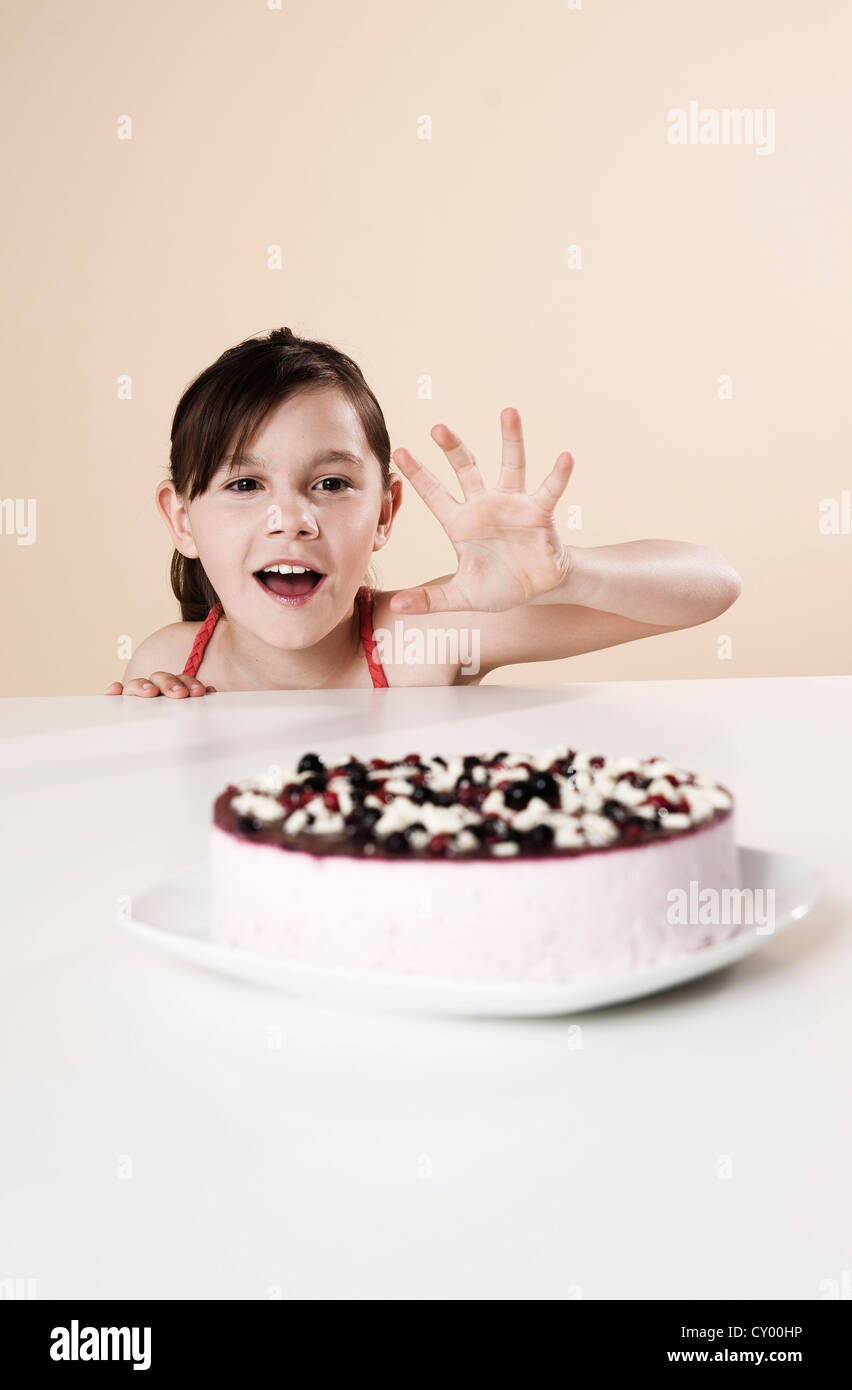 Girl reaching hungrily towards a cake Stock Photo - Alamy