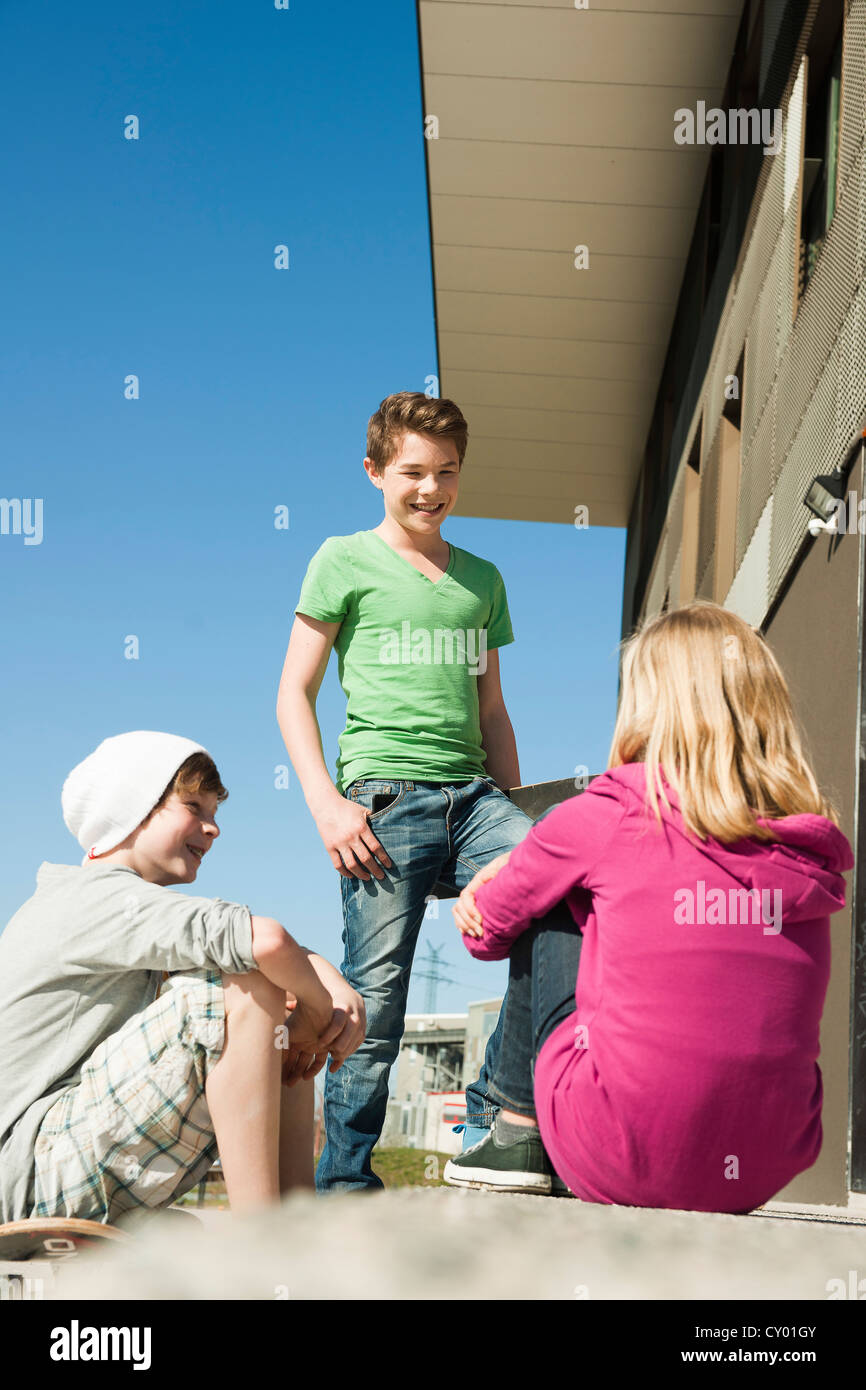 Three teenagers meeting in front of a building, chatting Stock Photo ...