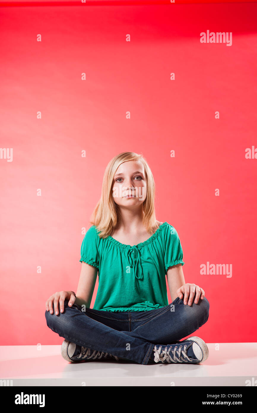 Girl sitting cross-legged with a serious expression Stock Photo - Alamy