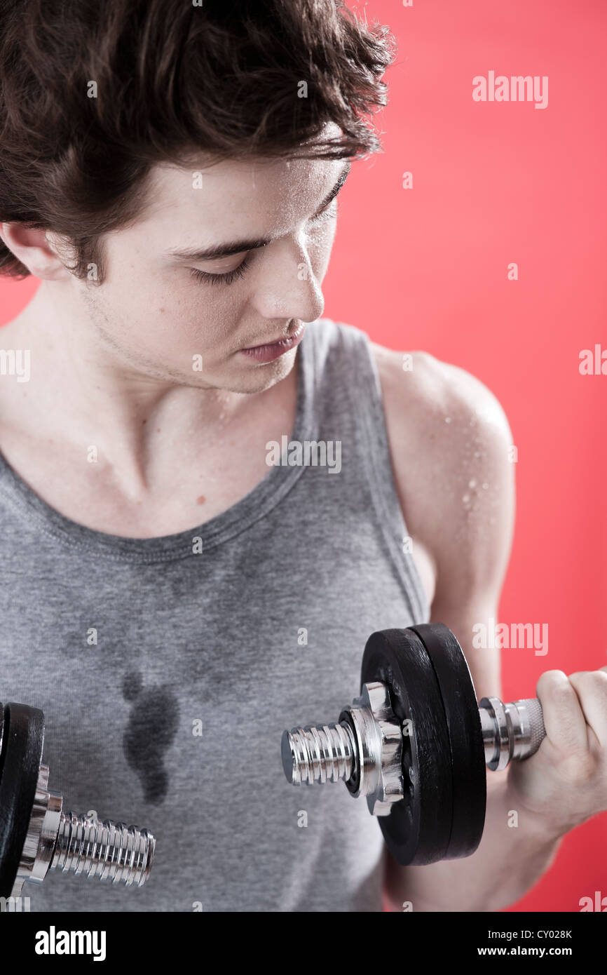 Young man using dumbbells during strength training Stock Photo - Alamy