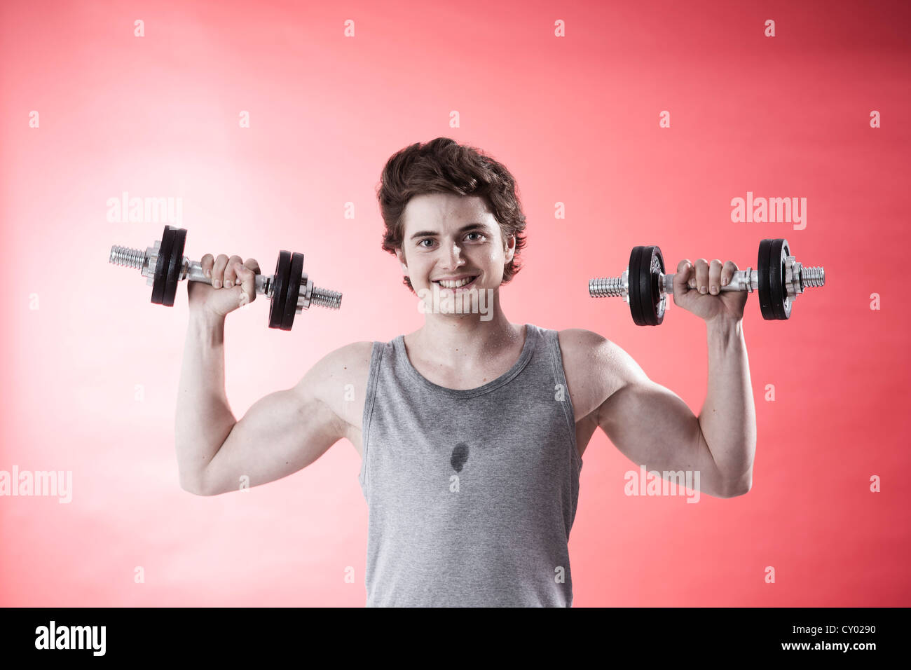 Young man using dumbbells during strength training Stock Photo - Alamy