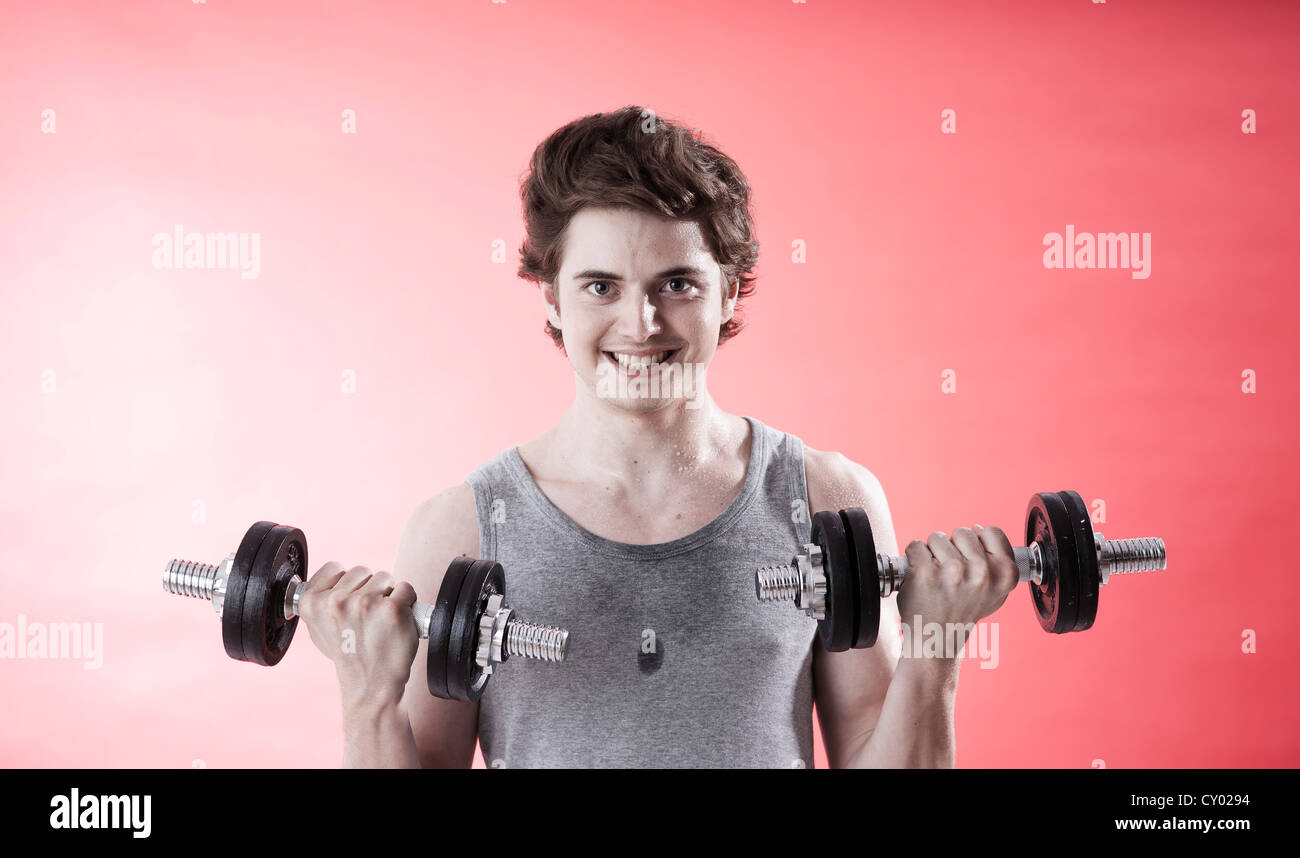 Young man using dumbbells during strength training Stock Photo - Alamy