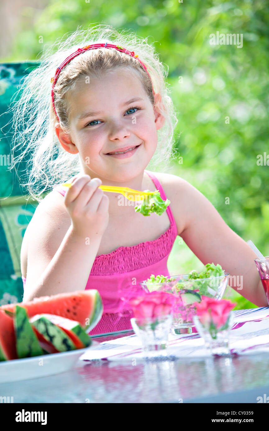 Girl eating salad at a garden table Stock Photo - Alamy
