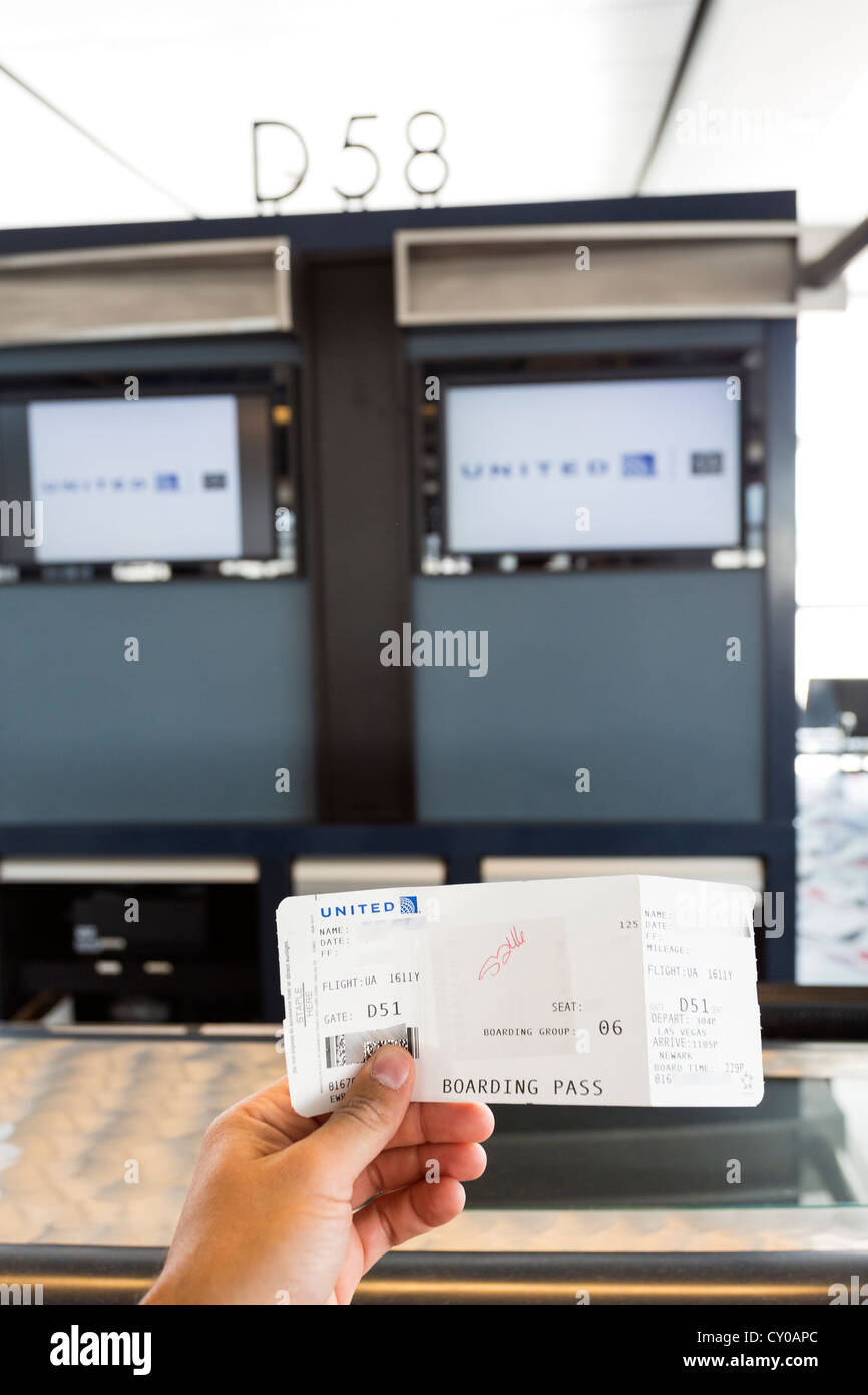 Hand holding a boarding pass. Airport gate in the background Stock ...