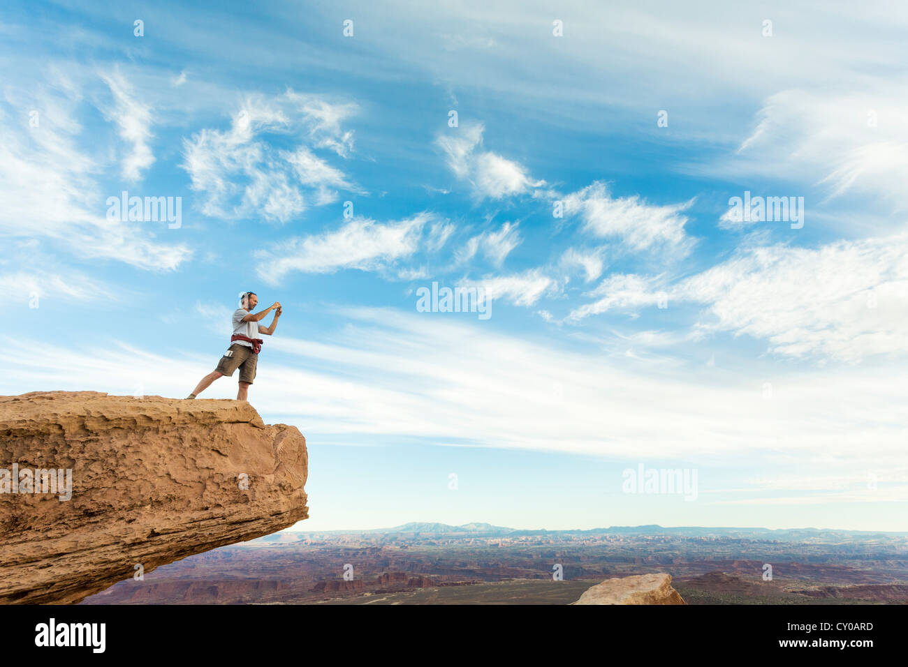 Man standing on the ledge photographing a beautiful landscape in ...