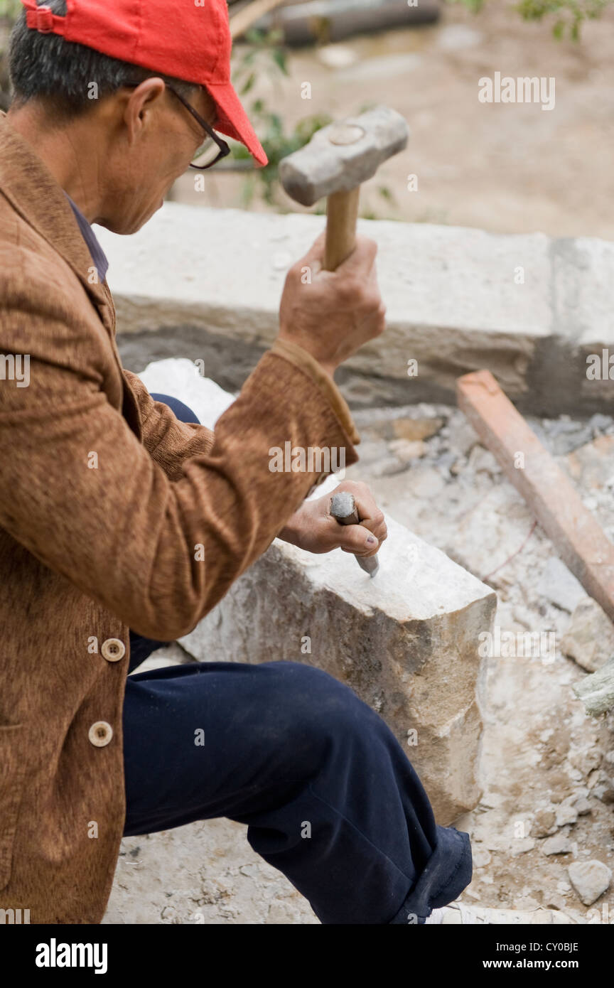 A man hammering a chisel on rocks at the San Huang Zhai Monastery on ...