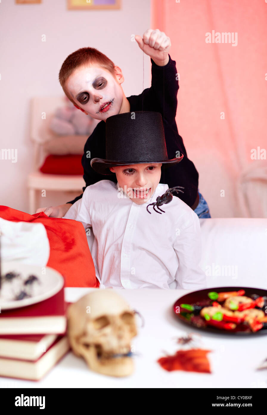 Photo of evil boy scaring his brother with spider on Halloween Stock ...