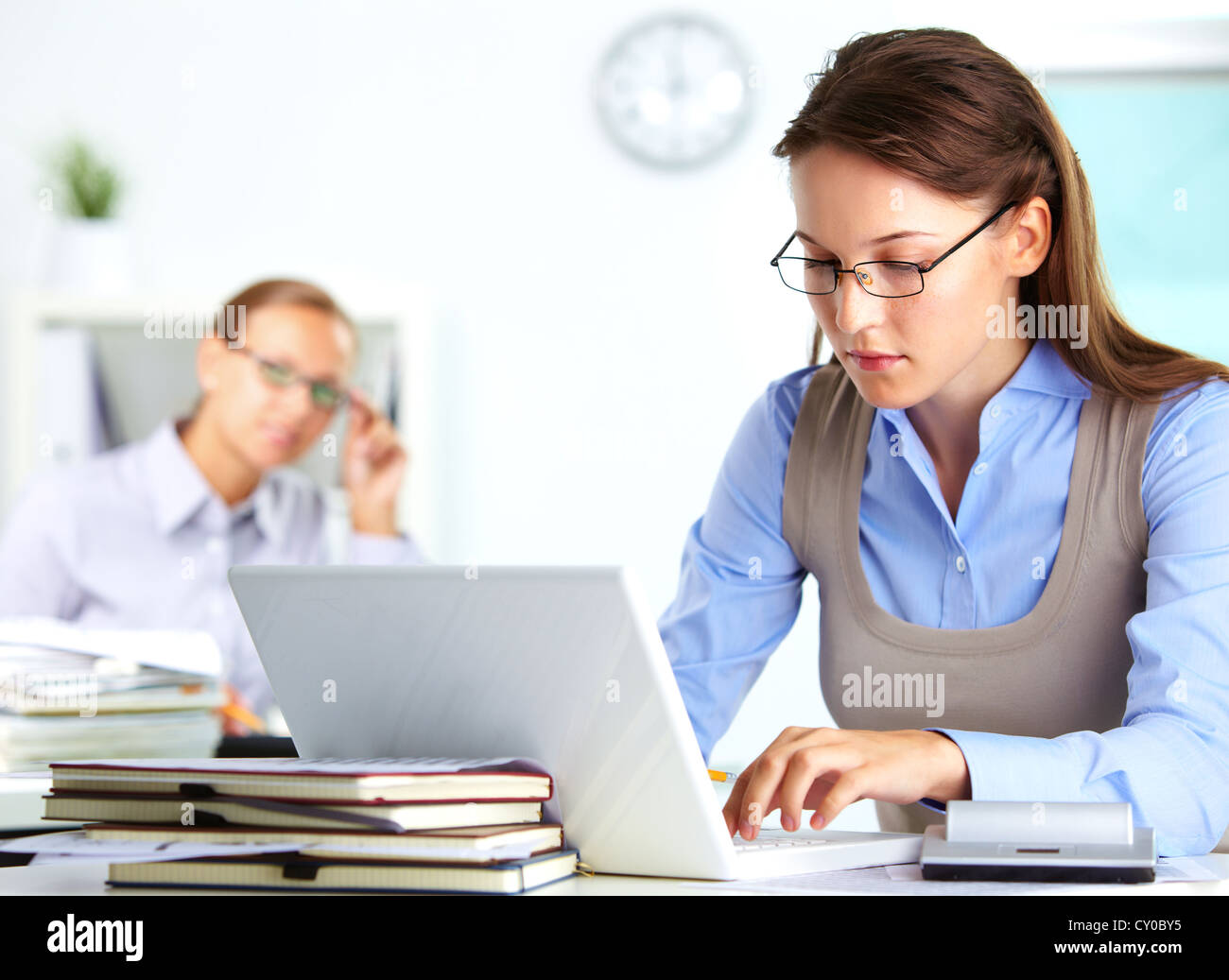Portrait of pretty secretary typing in office Stock Photo - Alamy