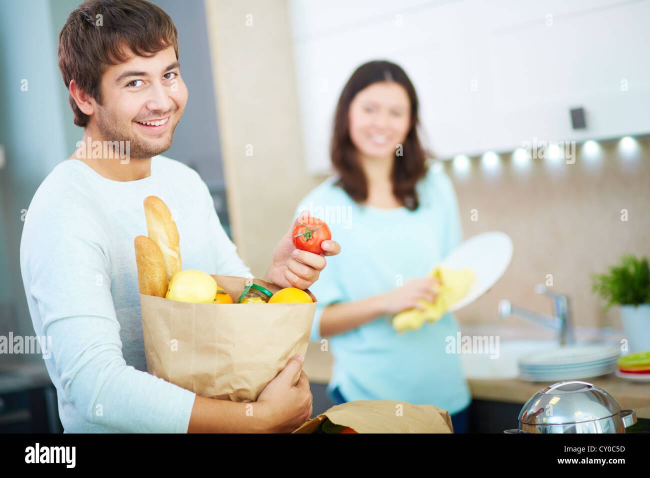 Young man with paper packet looking at camera in the kitchen Stock ...