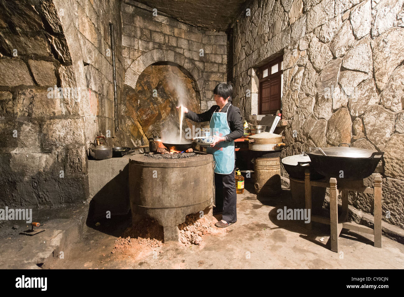 A woman cooks in a traditional Shaolin kitchen at the San Huang Zhai ...