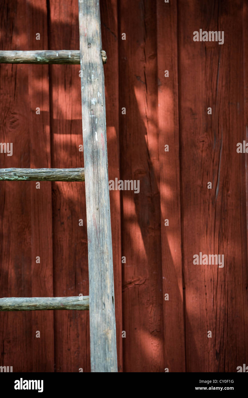 Empty ladder leaned against wall of red house Stock Photo - Alamy