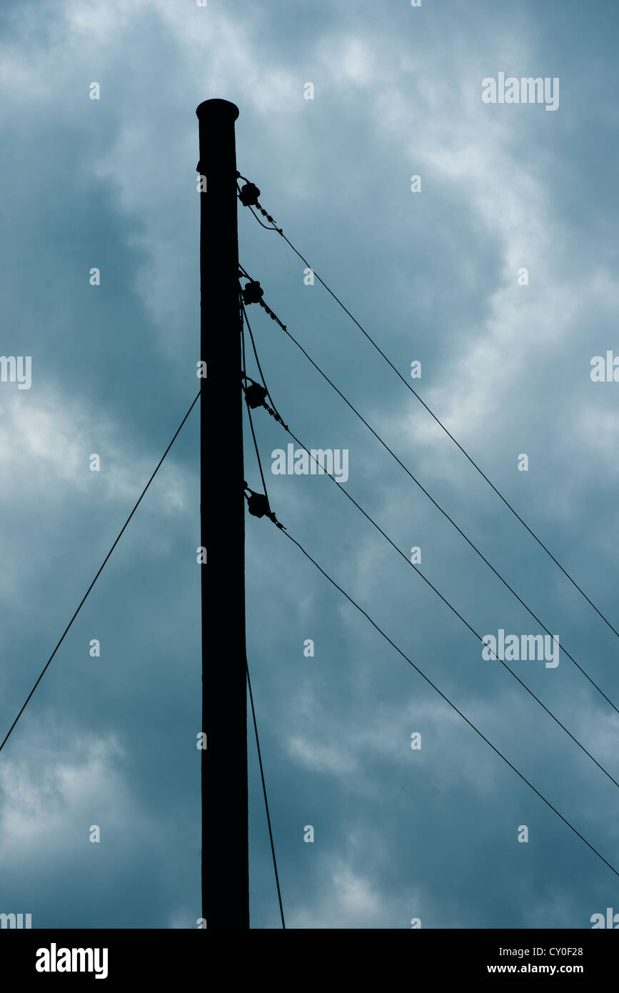 Dark sky with heavy clouds and wooden telephone mast with phone lines ...