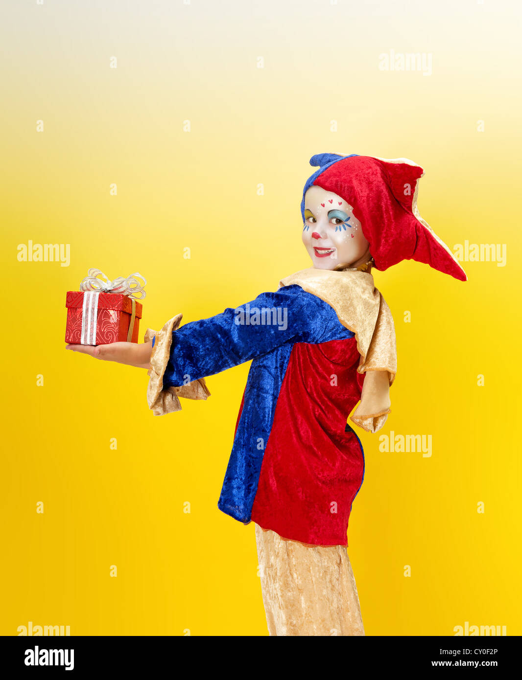 Cute little girl clown presenting a gift box Stock Photo - Alamy