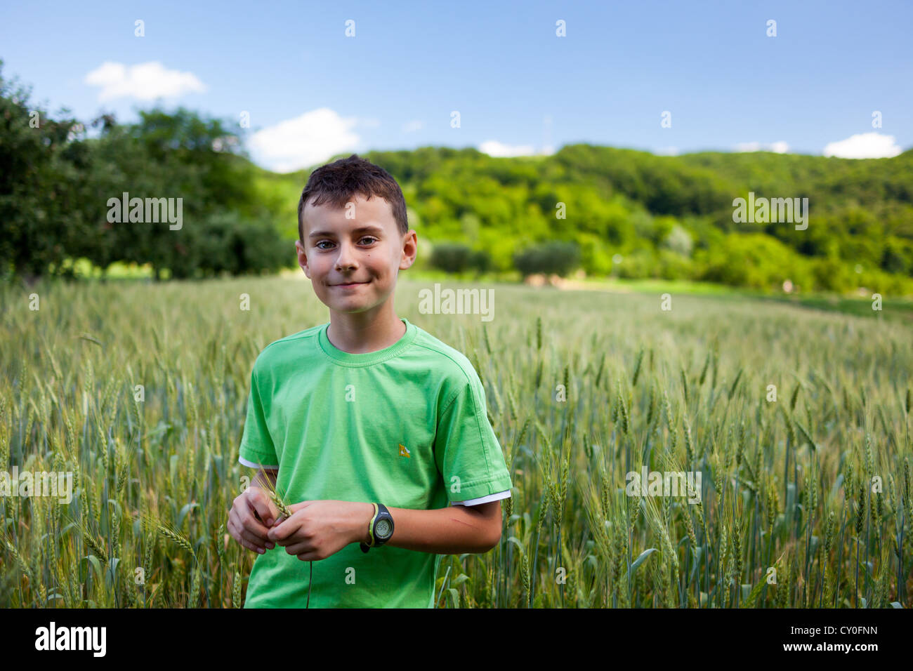 Closeup portrait of a child standing on a wheat field near the forest ...