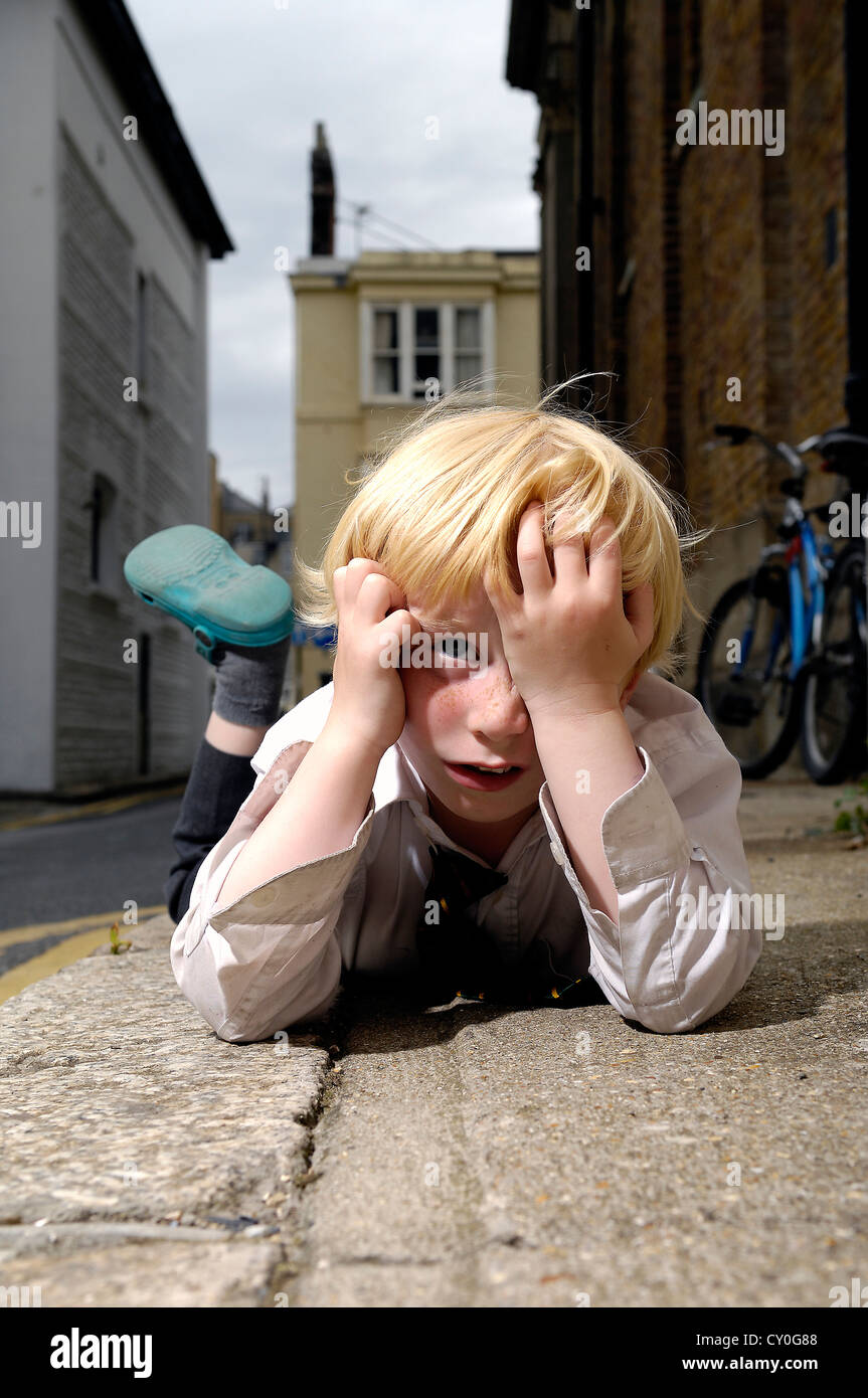 Young Boy Laying on Pavement Stock Photo - Alamy