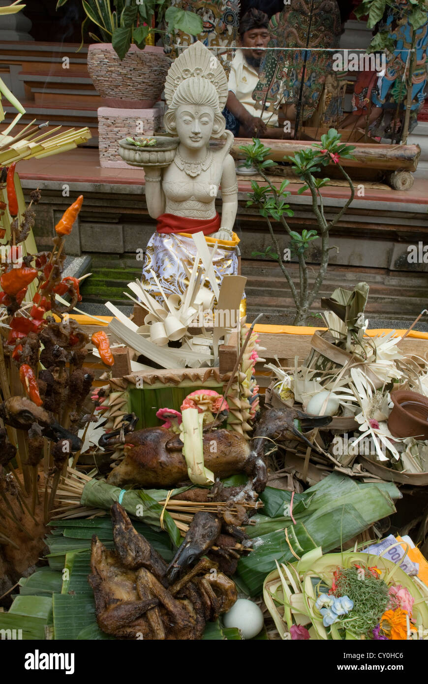 An Animist sculpture presides over offerings, including roasted ducks ...