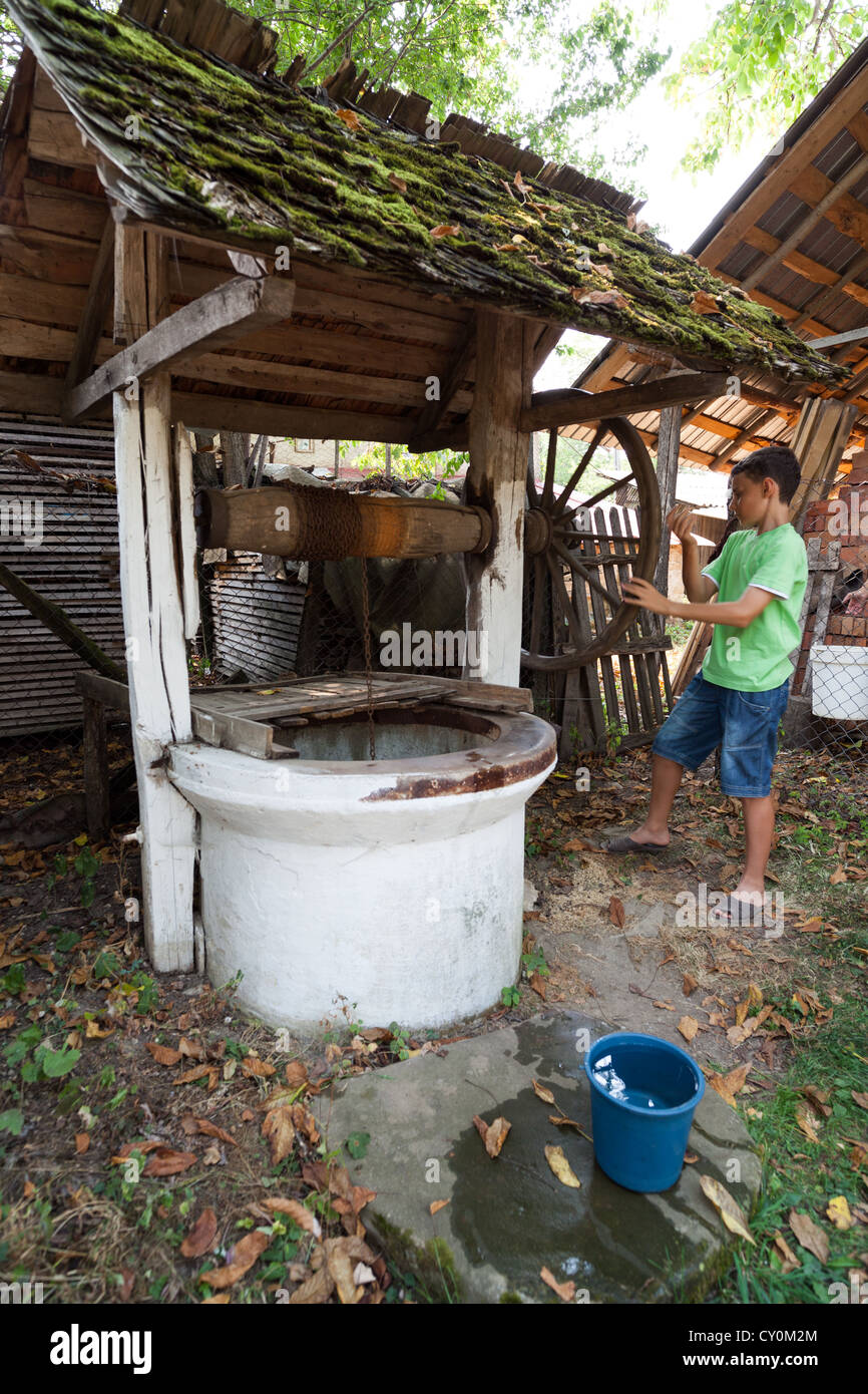 Full length portrait of a child getting water from a vintage wooden ...