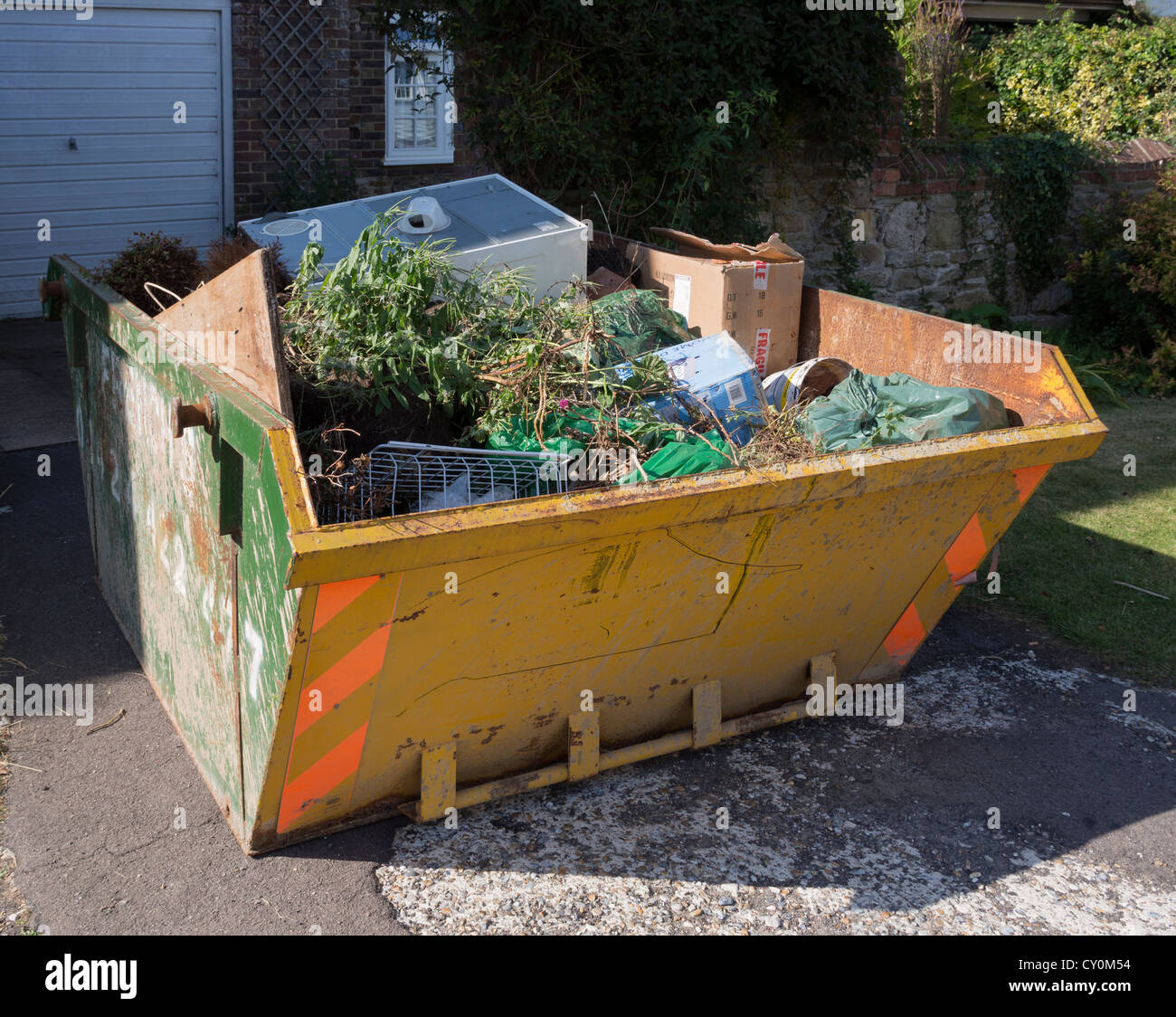 Skip filled with rubbish in a driveway Stock Photo - Alamy