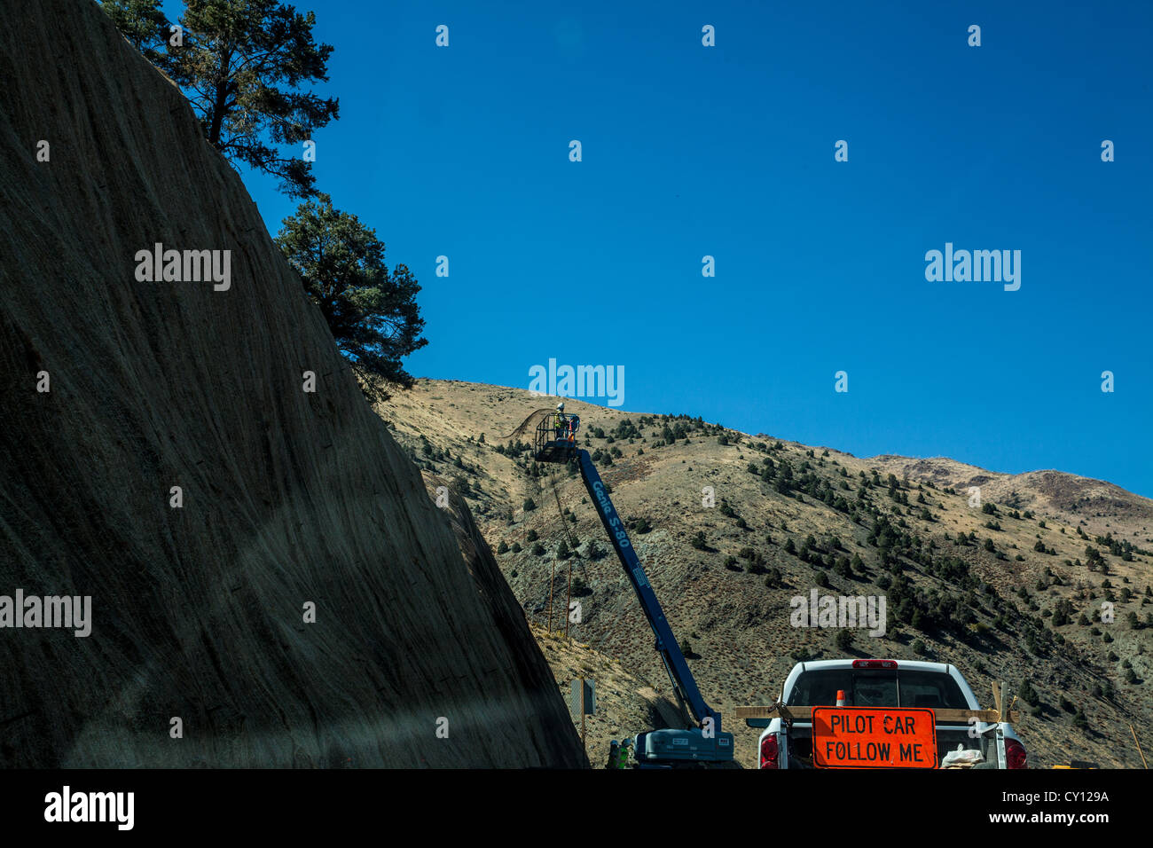 Men working on a carved hillside placing netting, on a road project at ...