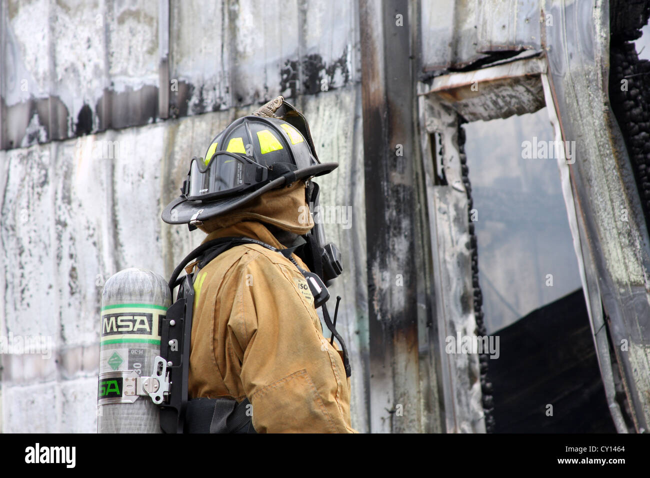 A firefighter standing in front of the ruins of an industrial building ...