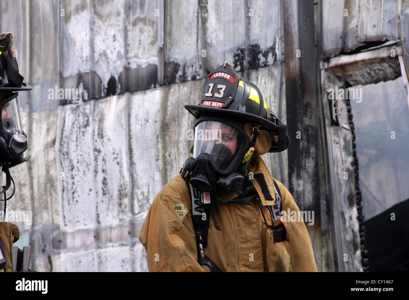 A woman firefighter at the scene of a fire in an industrial building ...