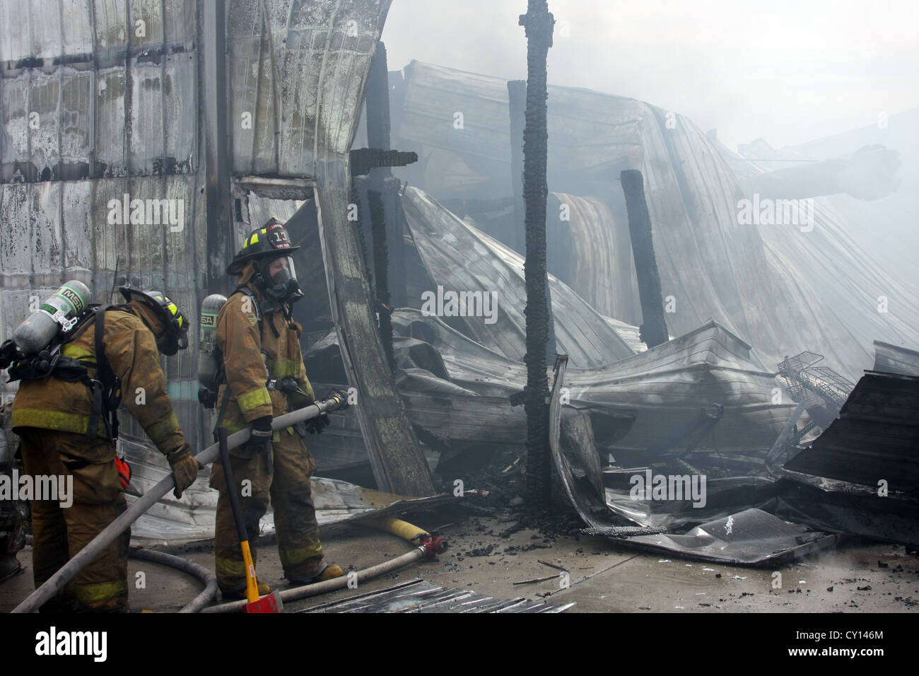 A woman and man firefighter at the scene of an industrial fire where ...