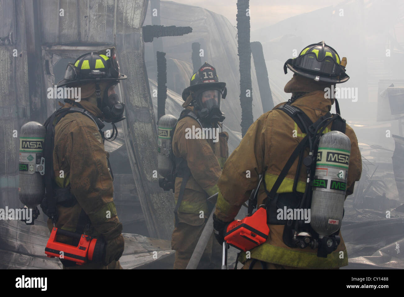 Three firefighters at a scene of an industrial fire and roof collapse ...