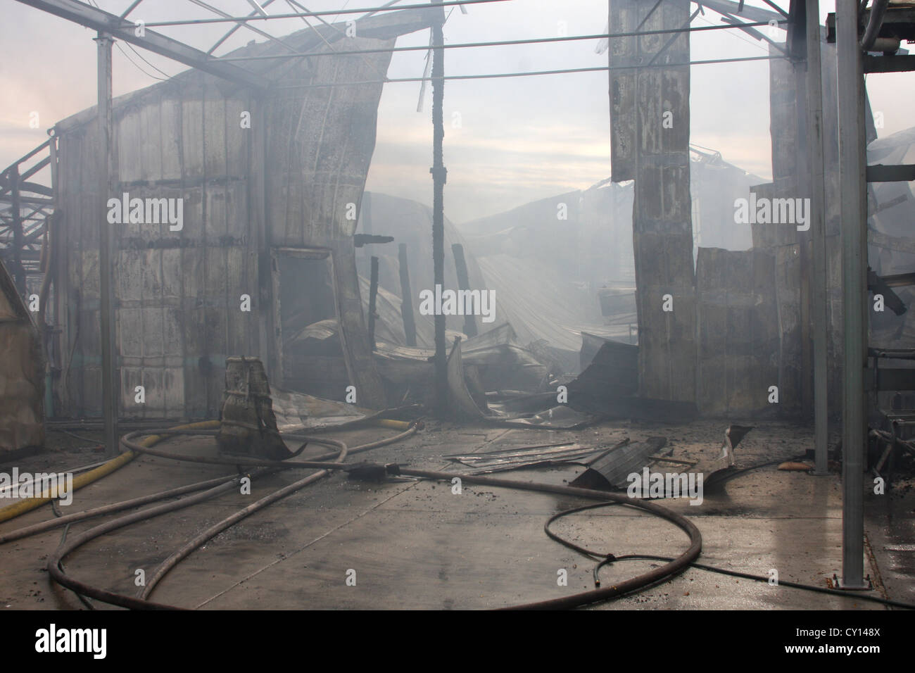 The scene of the aftermath of a fire in an metal building with a roof ...