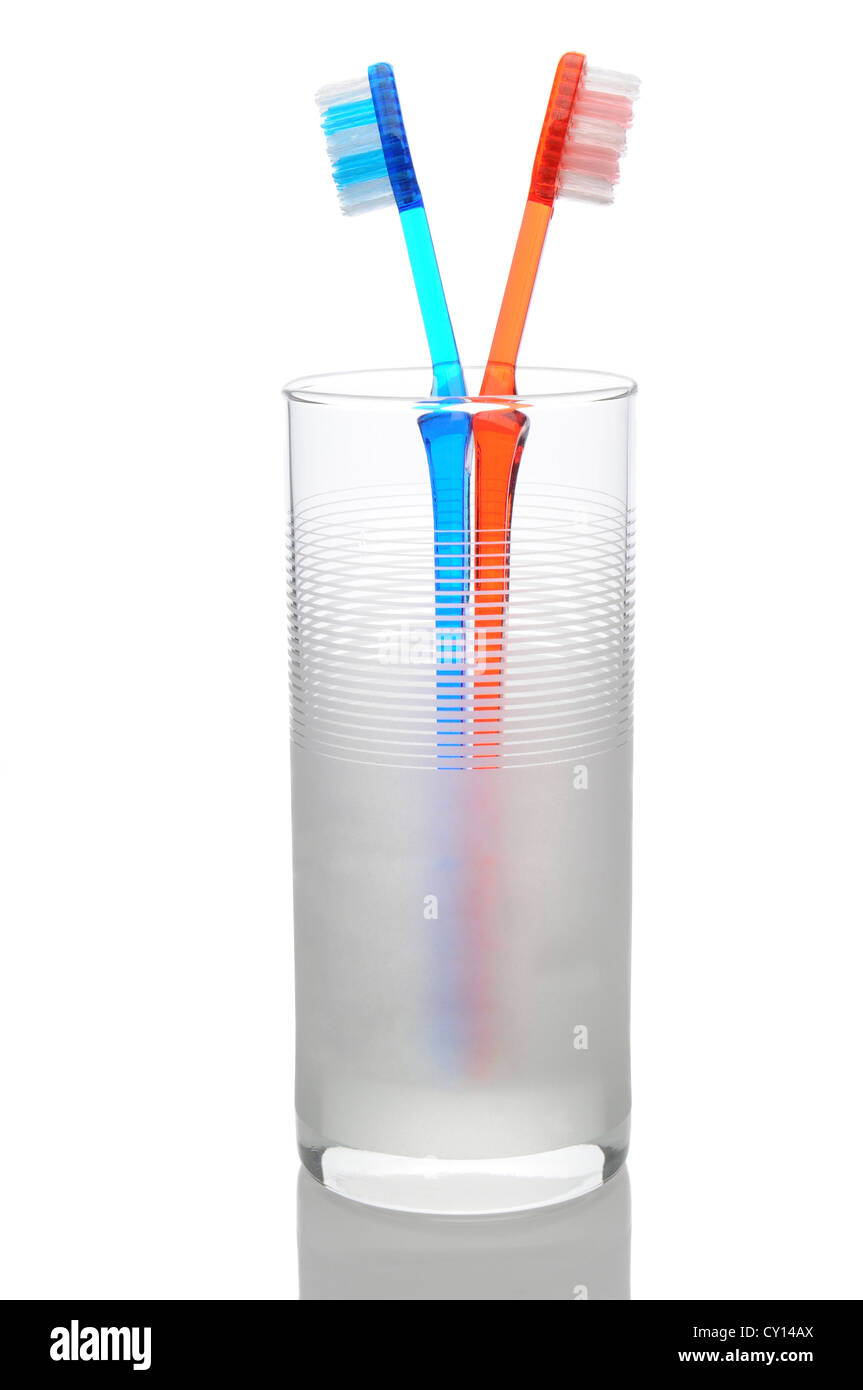A red and blue toothbrush standing in a frosted water glass. Vertical ...