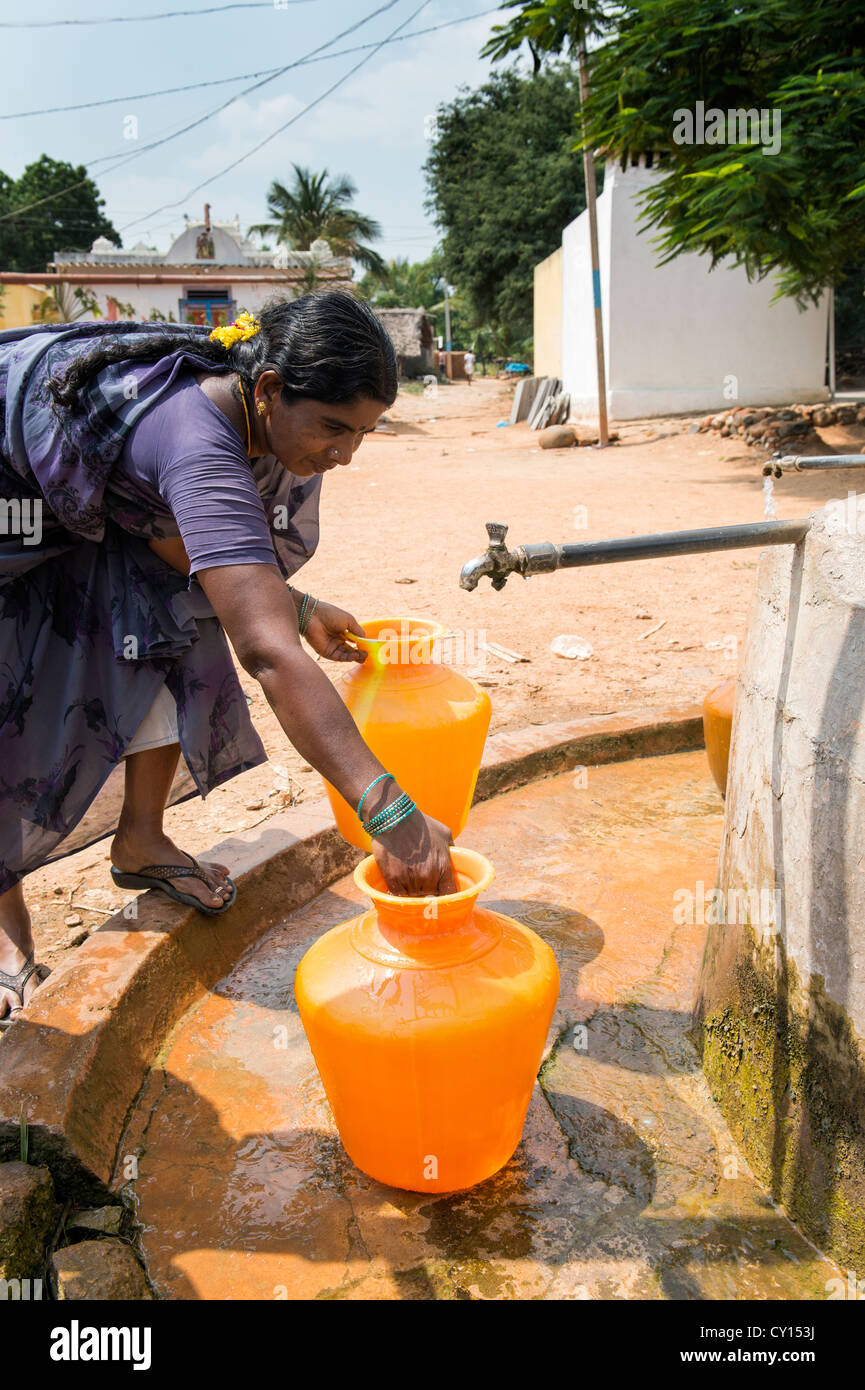 Rural Indian village woman collecting water from a communal water tank ...
