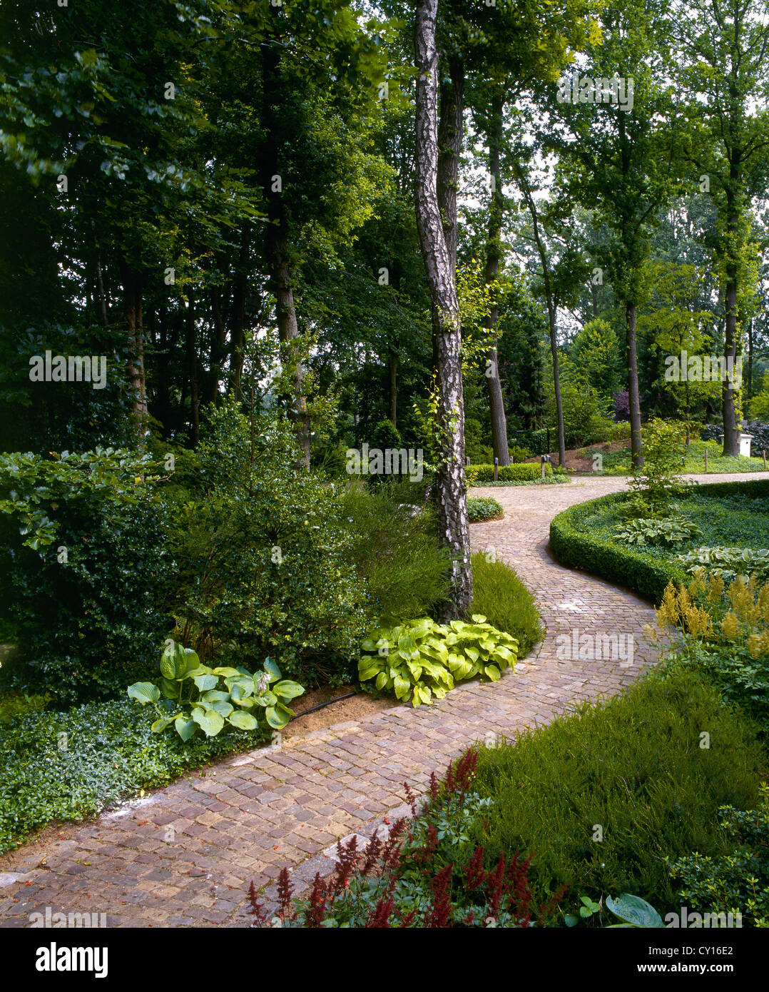 A brick paving stone path through a beautiful garden Stock Photo - Alamy