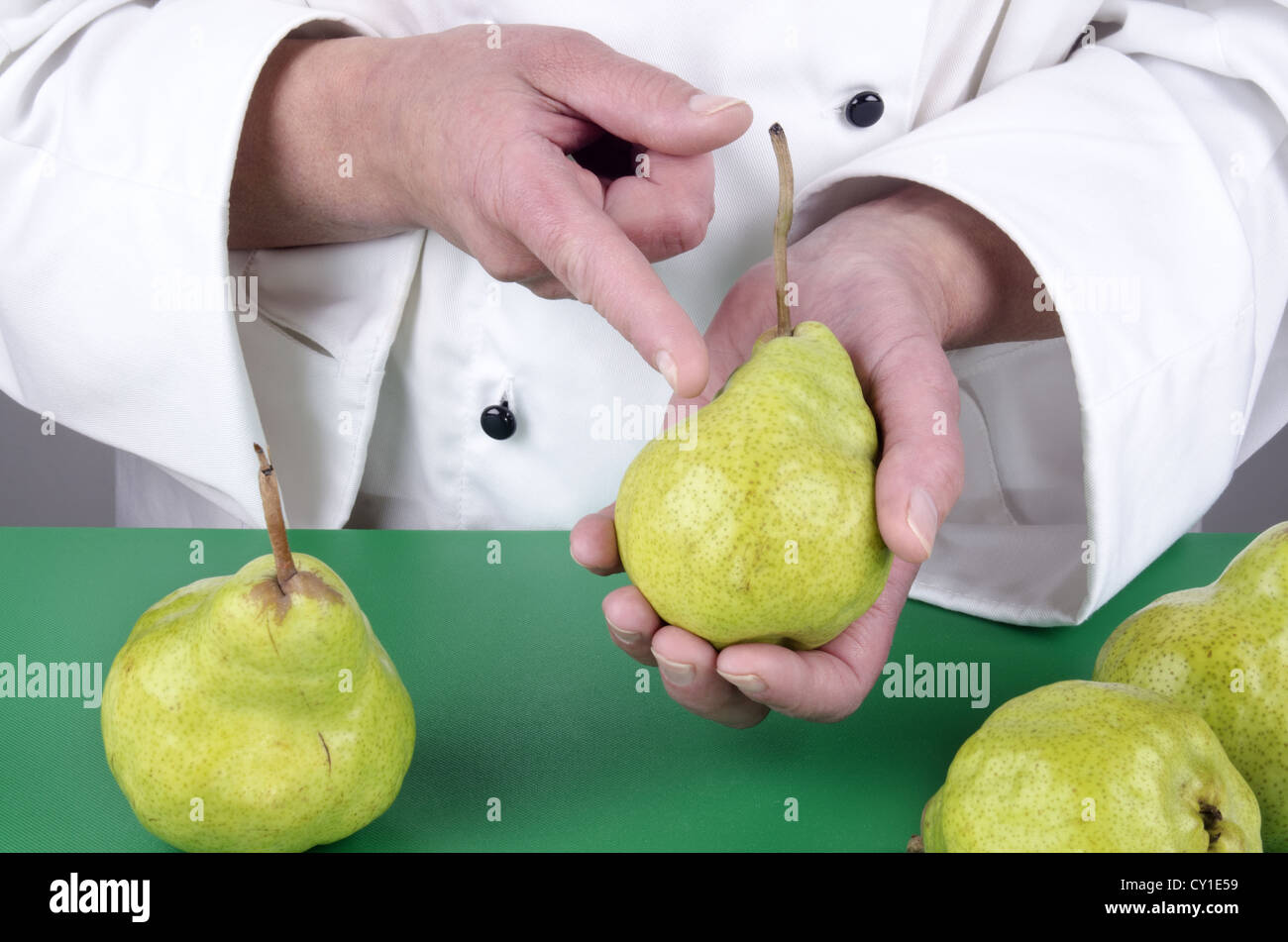 female chef in uniform shows with her index finger on a pear Stock ...