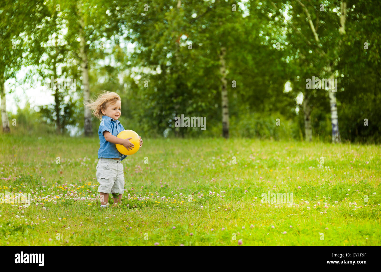little football player standing on the field and holding yellow ball ...