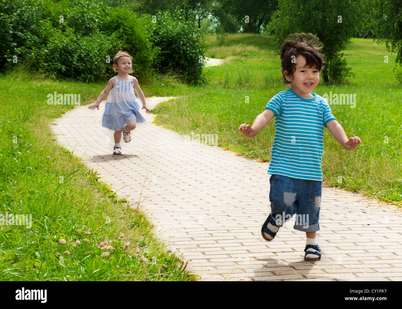 little girl chasing cute little boy in the park Stock Photo - Alamy
