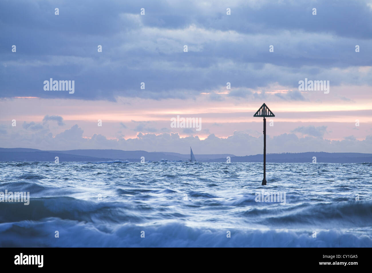 Sunset surf with small sailing boat in distance Stock Photo - Alamy