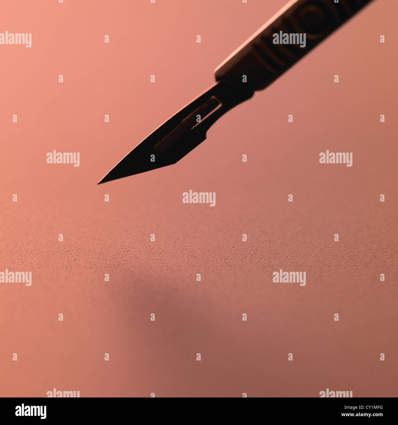 Surgical scalpel closeup with blade tip above surface, colour tinted ...