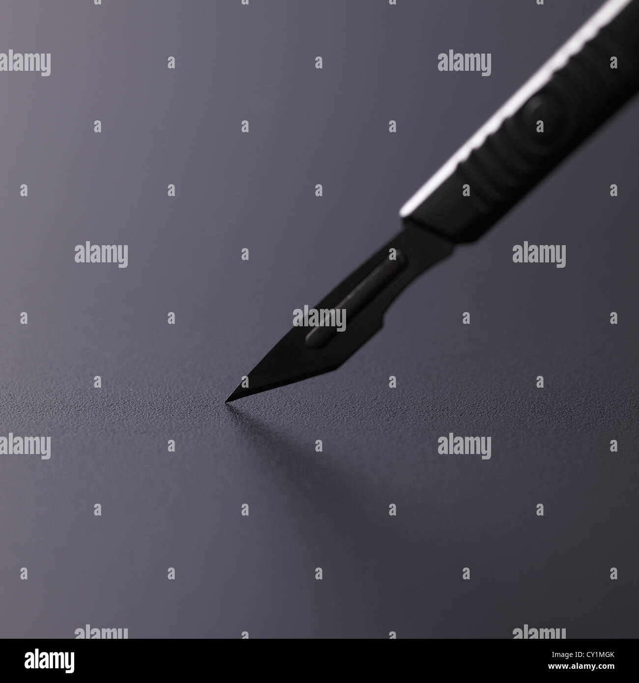 Surgical scalpel closeup with blade tip touching grey metallic worktop ...