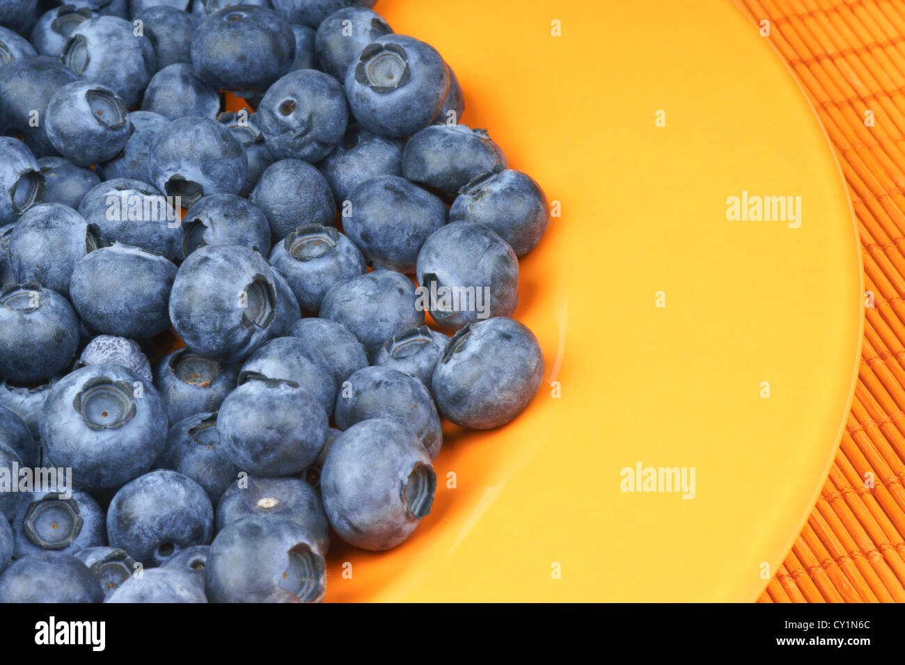 Close-up of some fresh blueberries in an orange plate over an orange ...