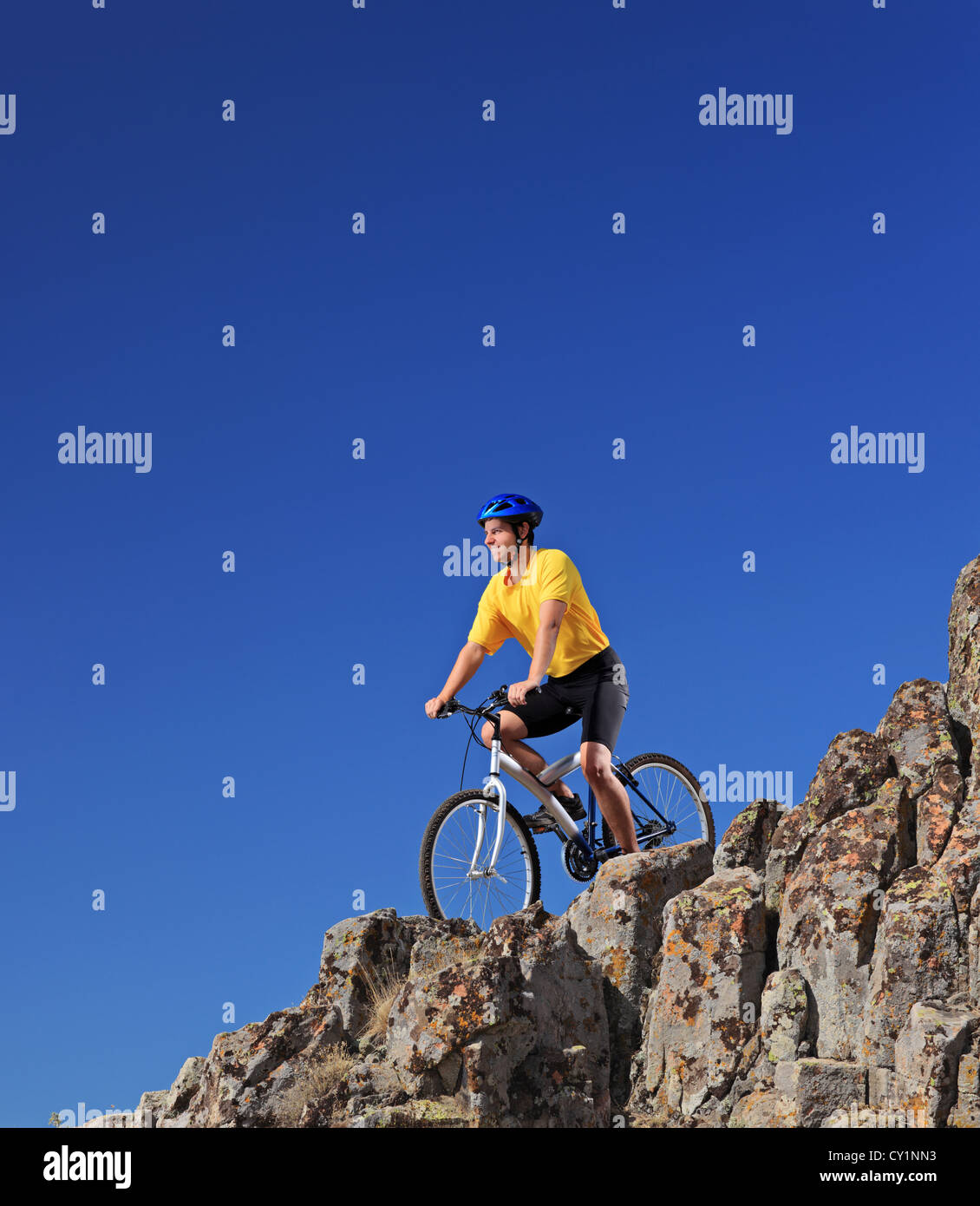Person riding a mountain bike on rocks on a sunny day against a blue ...