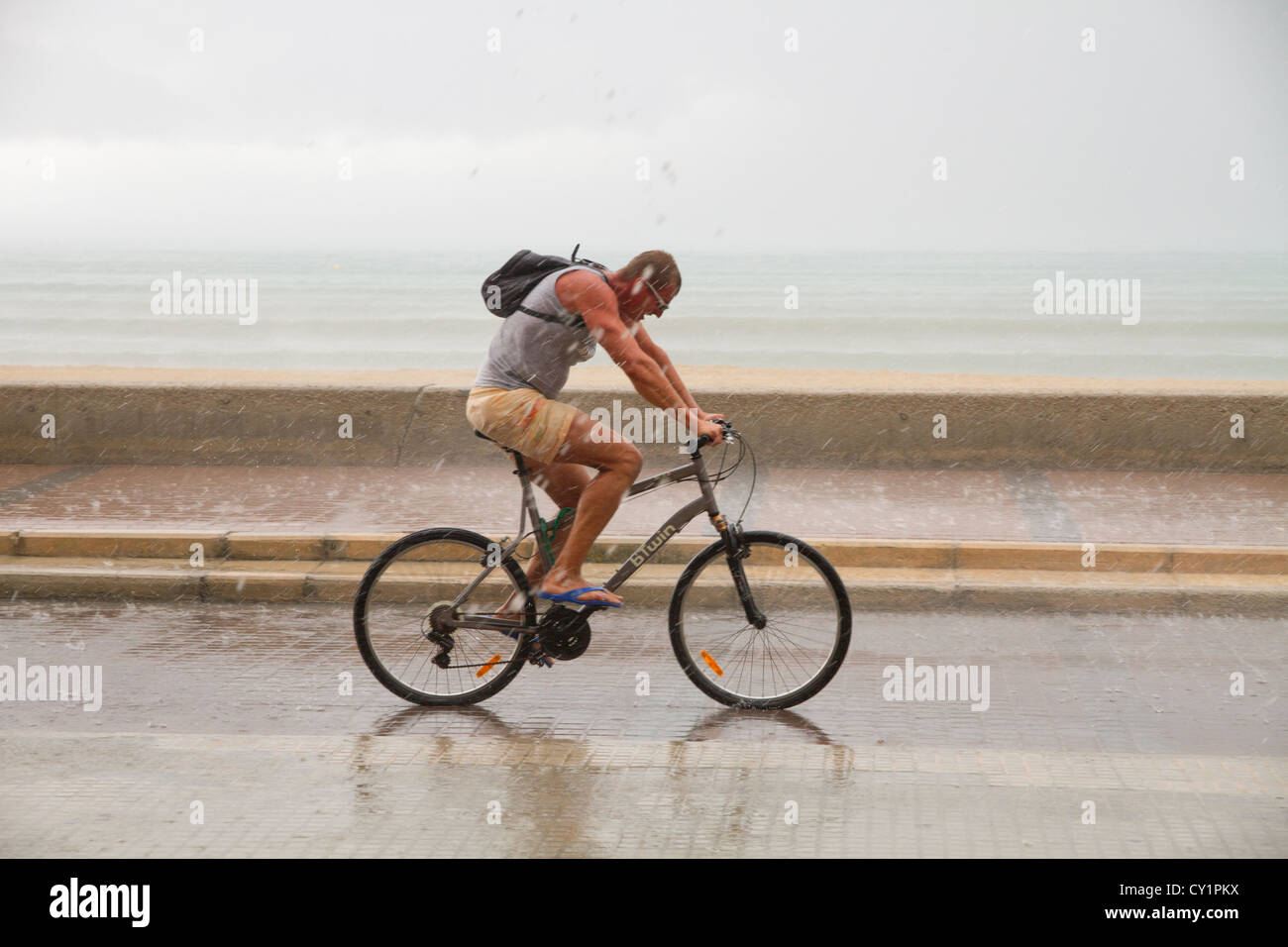 wet cyclist run fast during summer raining raining Stock Photo - Alamy