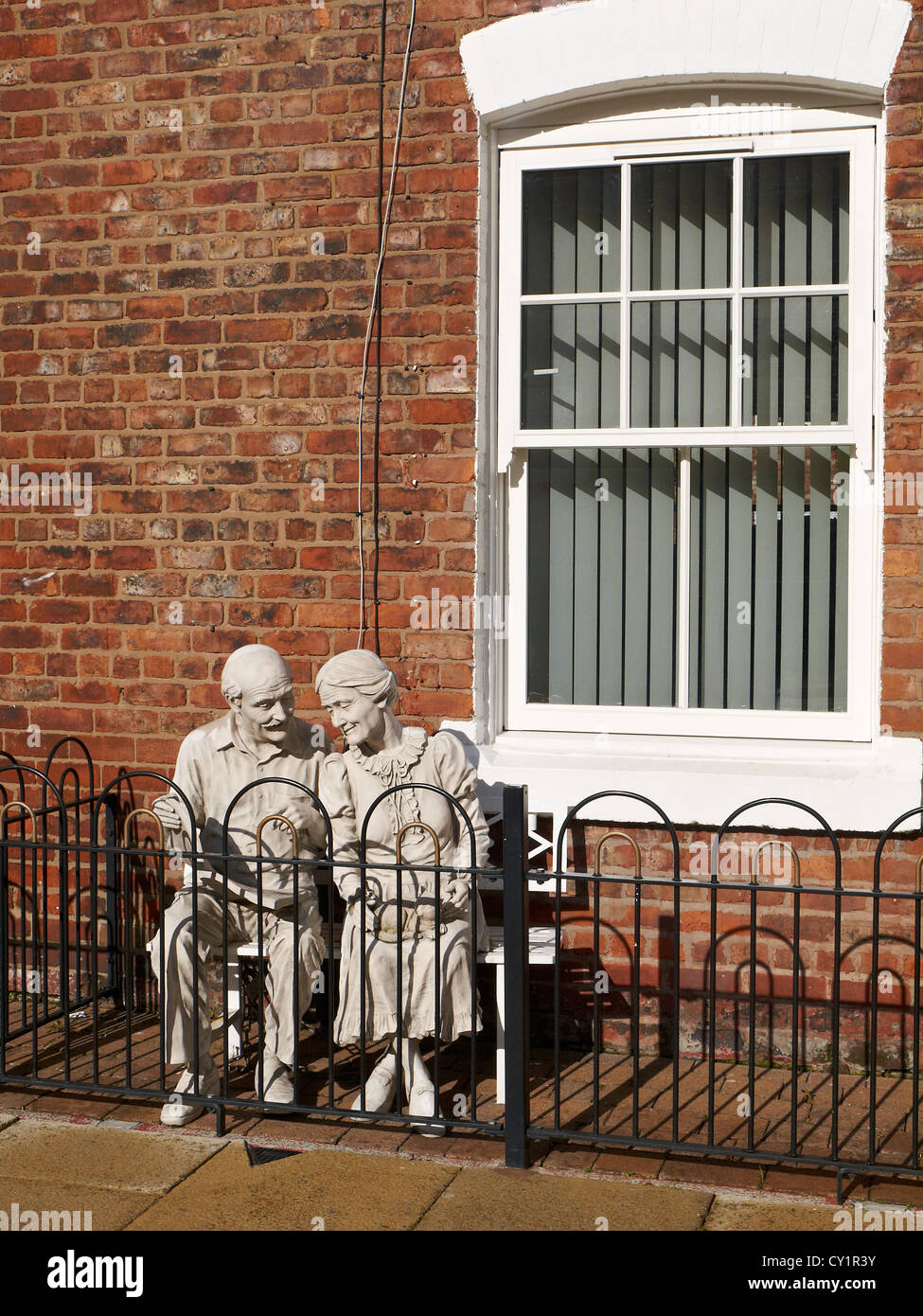 Statue of retired couple sitting on a bench in the front of a private ...