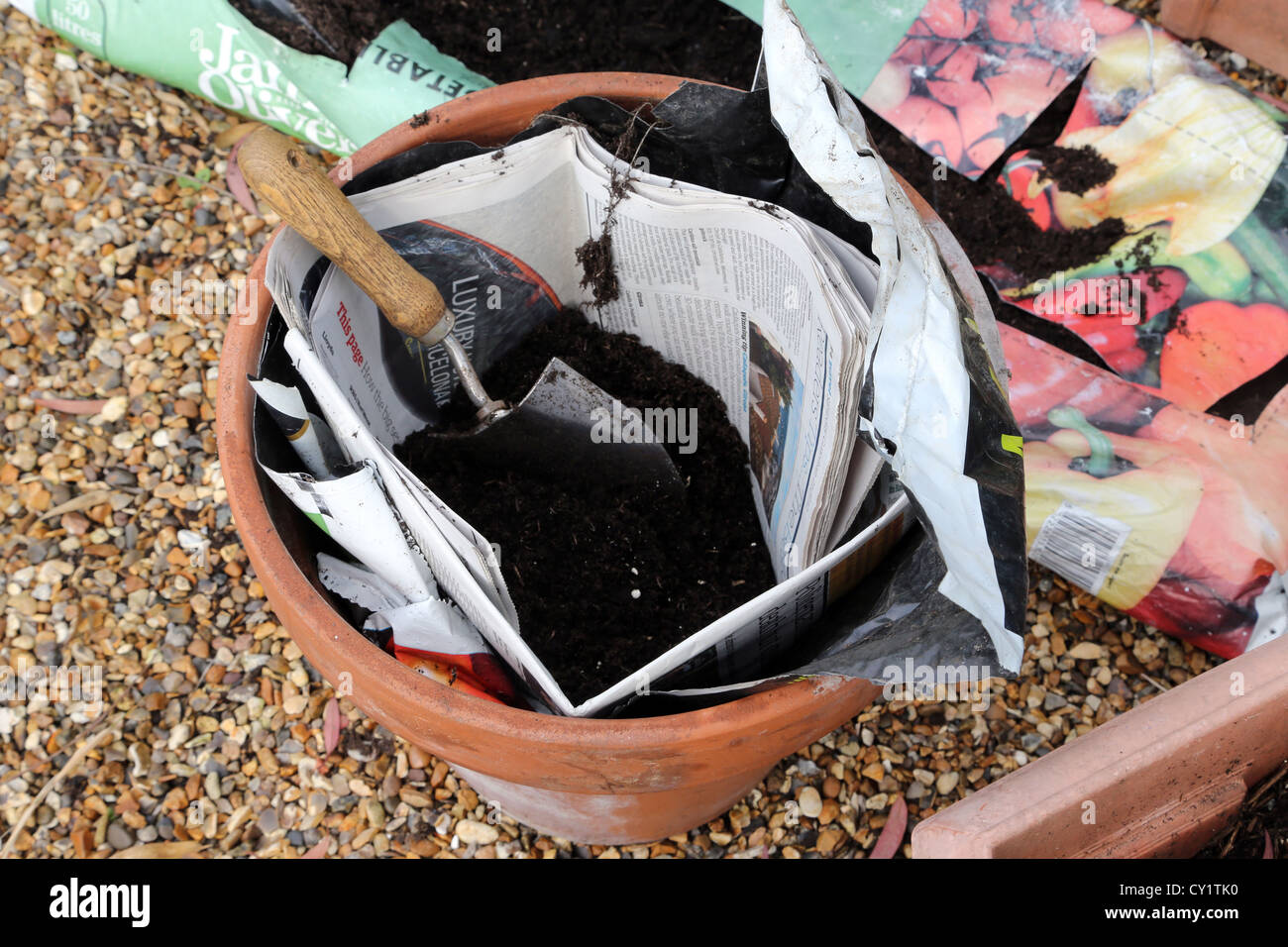 Lining a clay pot with plastic and newspaper Stock Photo - Alamy