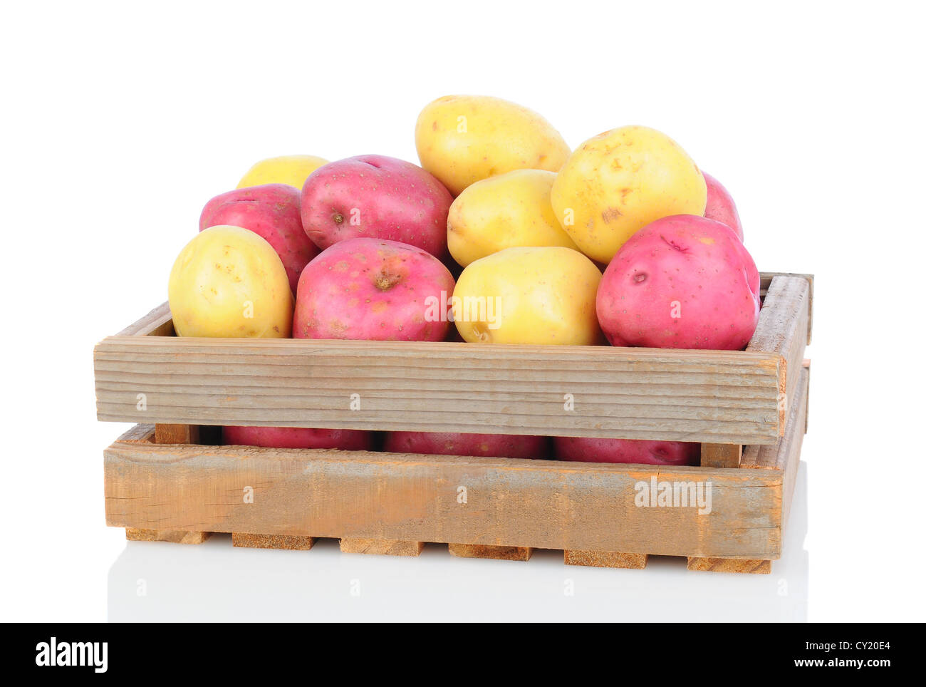 A wooden crate full of red and white potatoes on a white background ...