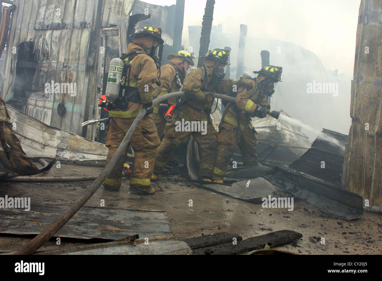 Firefighters on the scene of a fire dousing the flames Stock Photo - Alamy
