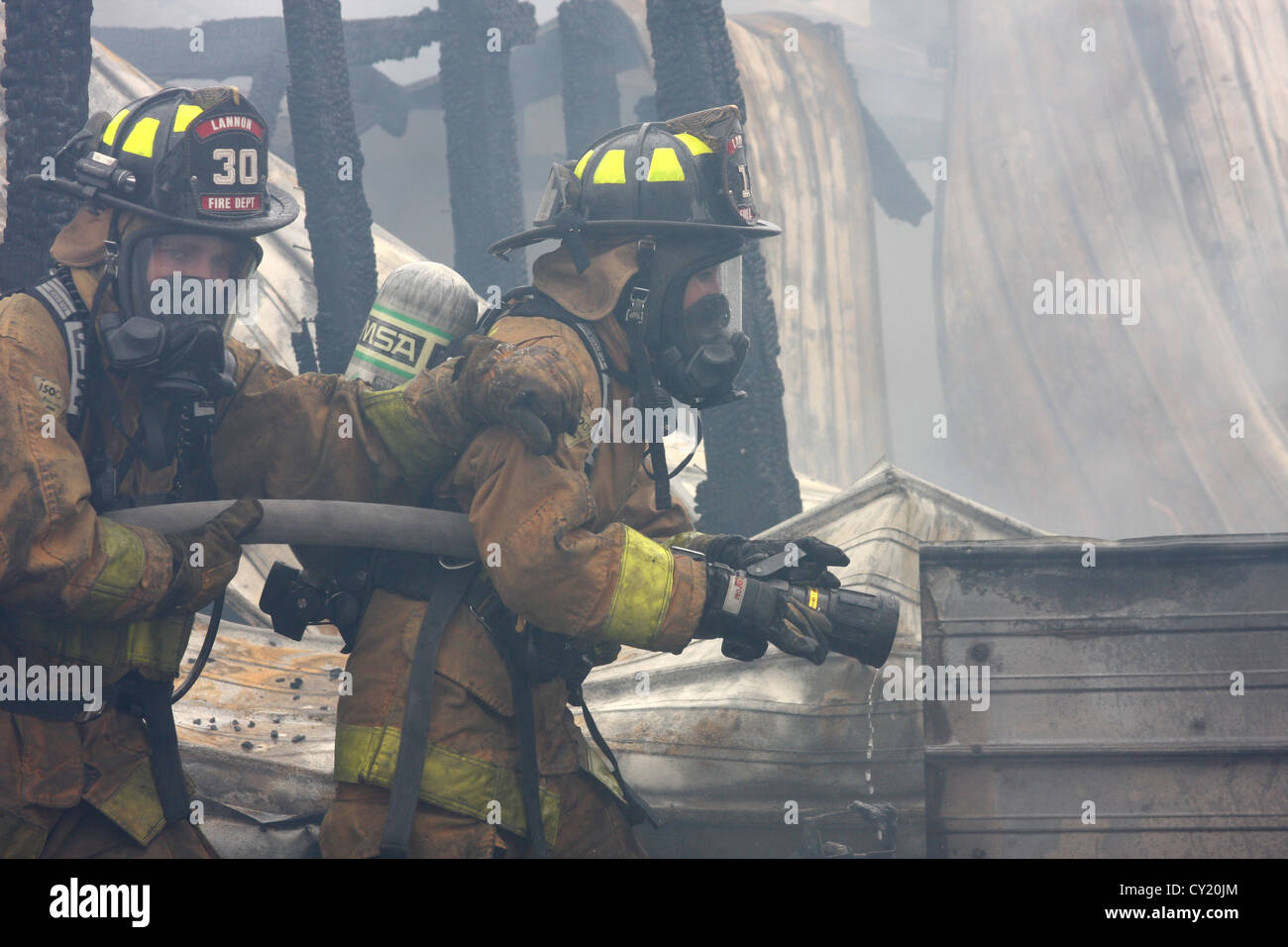 Firefighting team fighting a fire with a waterline Stock Photo - Alamy